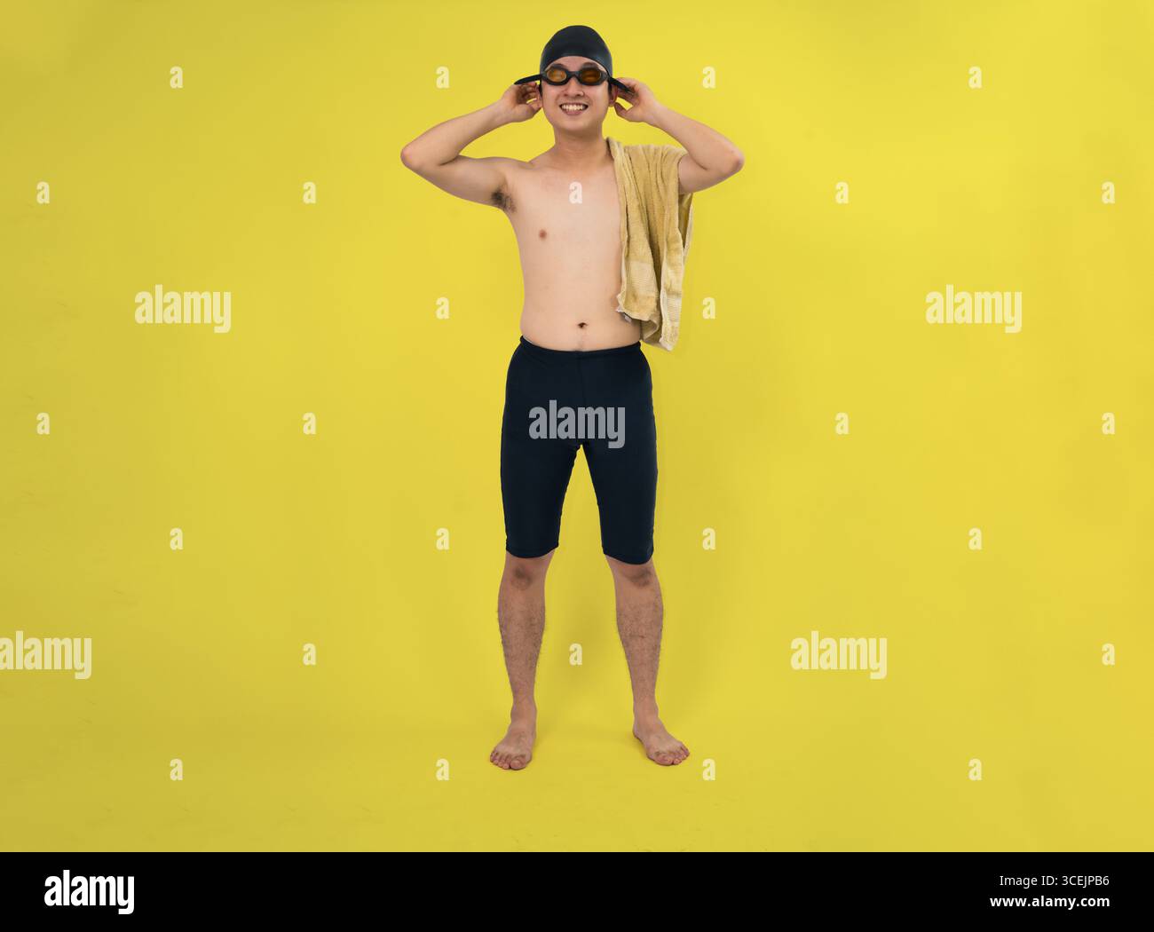 confident swimmer holding towel against yellow background in studio ...