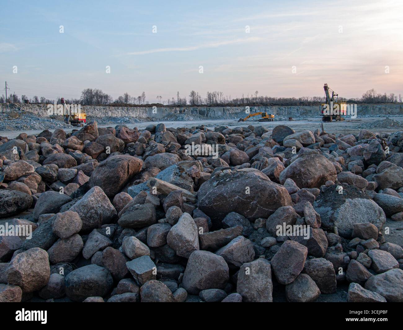 Open-pit quarry at Harku, Estonia, with heavy machinery and rock piles ...