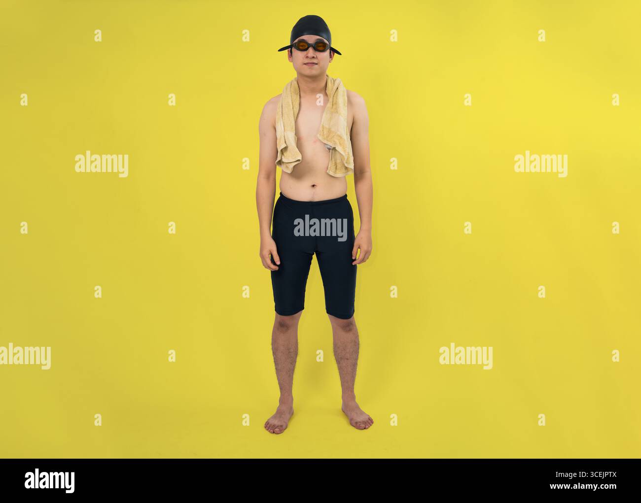confident swimmer holding towel against yellow background in studio ...