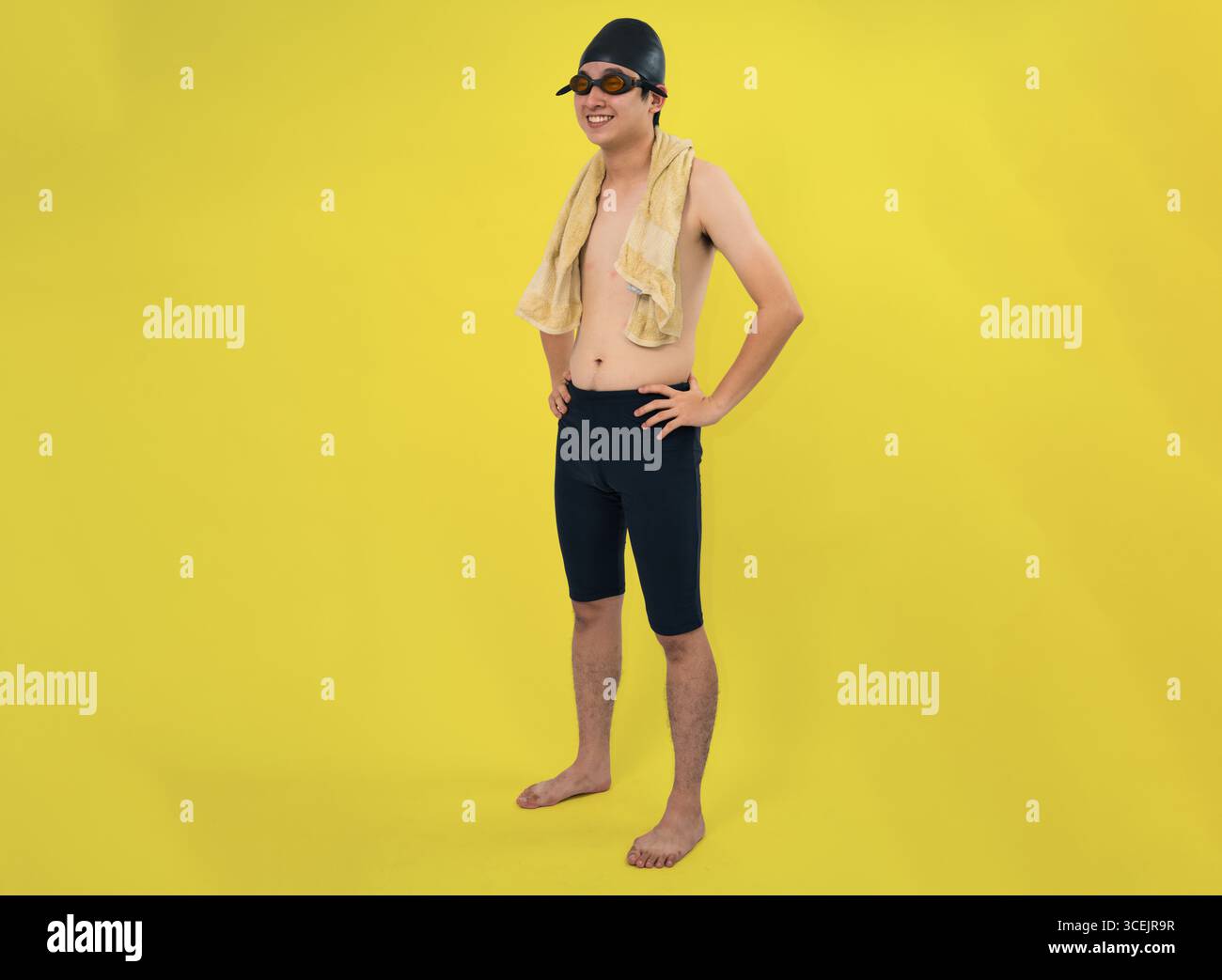 confident swimmer holding towel against yellow background in studio ...