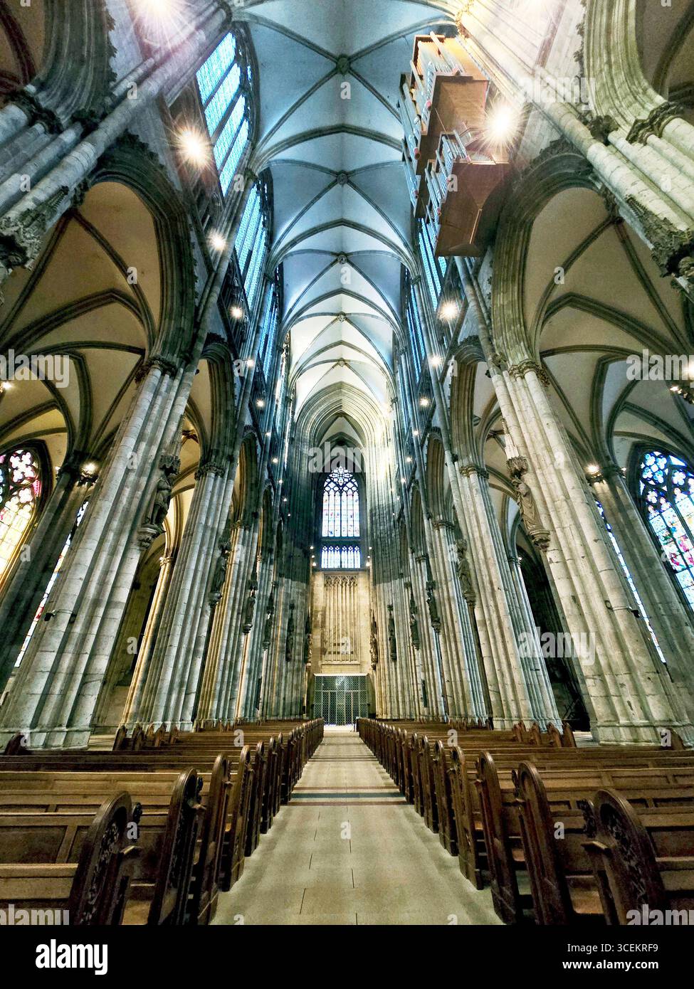 Side aisle with pointed arches, stone columns and stained-glass windows ...