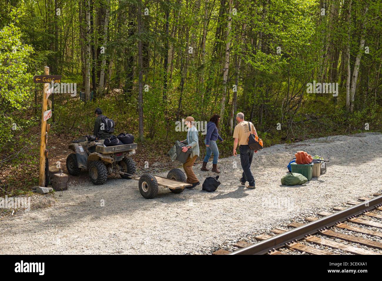 People loading supplies onto small motorized 4-wheel quad and trailer ...