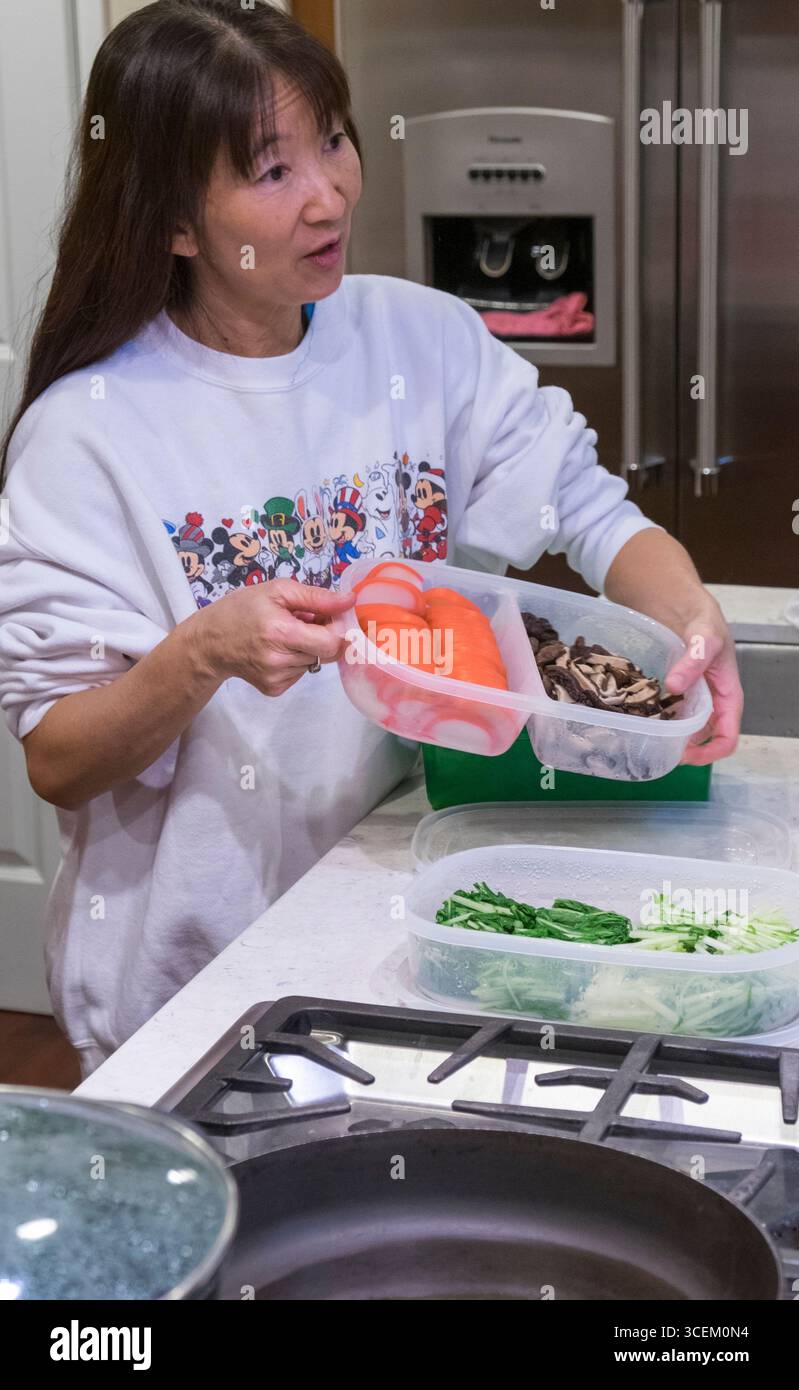 Mature Japanese woman holding ingredients in plastic tray used to make ...