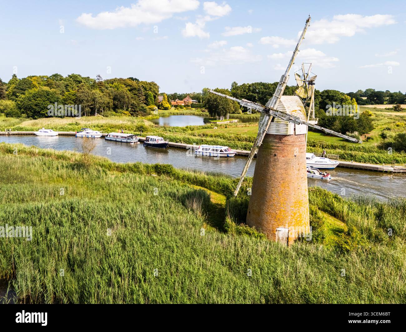 An old windmill seen next to boats along the River Bure near Ludham ...