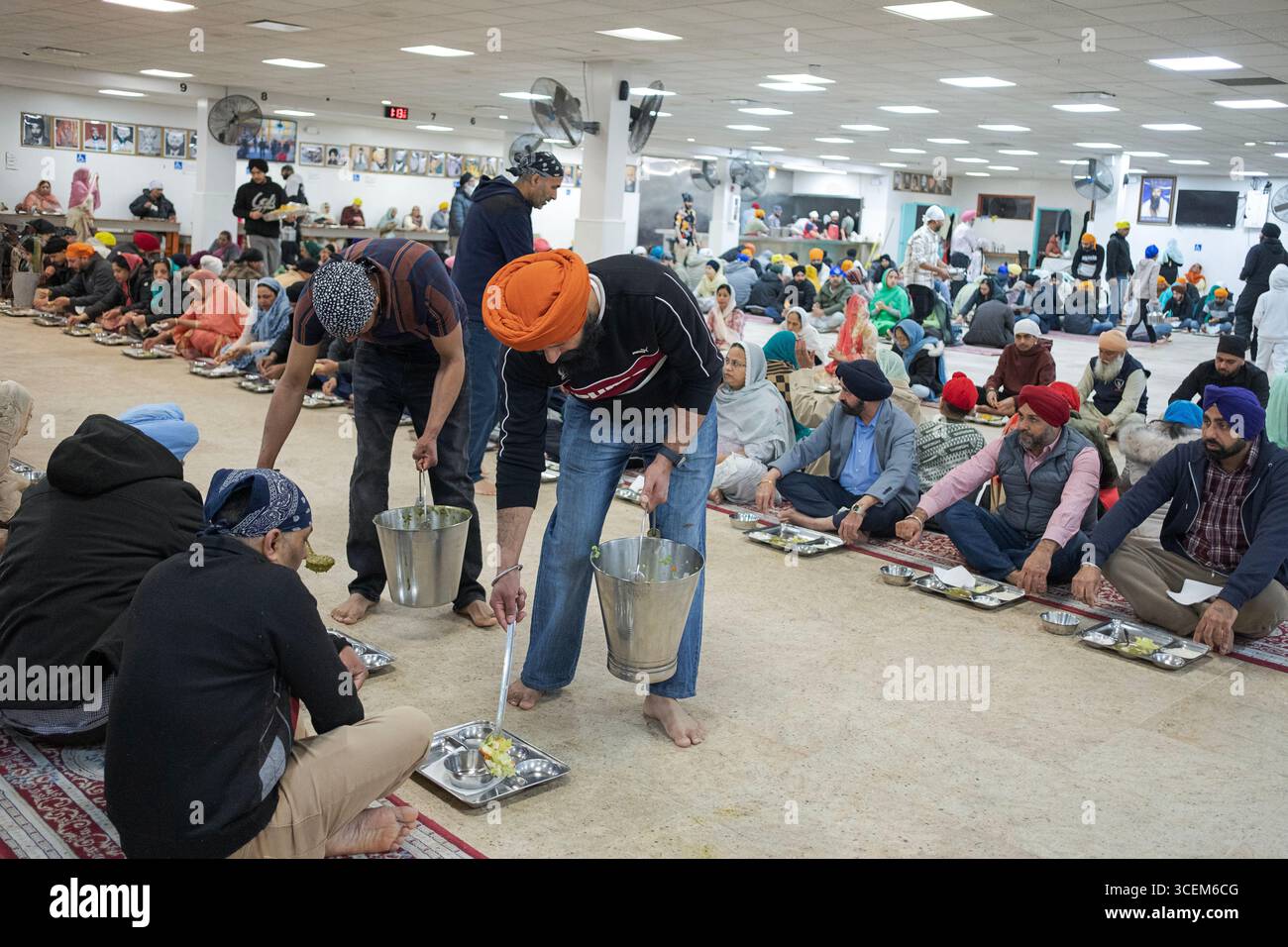 Devout Sikh men serve free vegetarian food at a Sikh temple langar, a ...