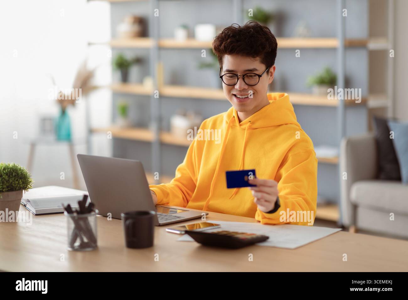 Smiling asian guy using credit card and pc Stock Photo - Alamy