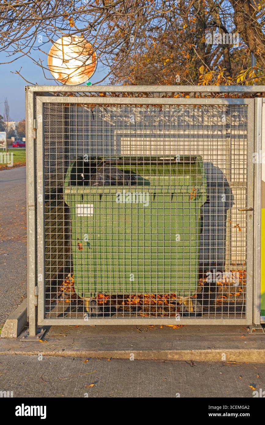 Green Plastic Trash Recycling Bin Enclosed in Wire Cage Stock Photo - Alamy