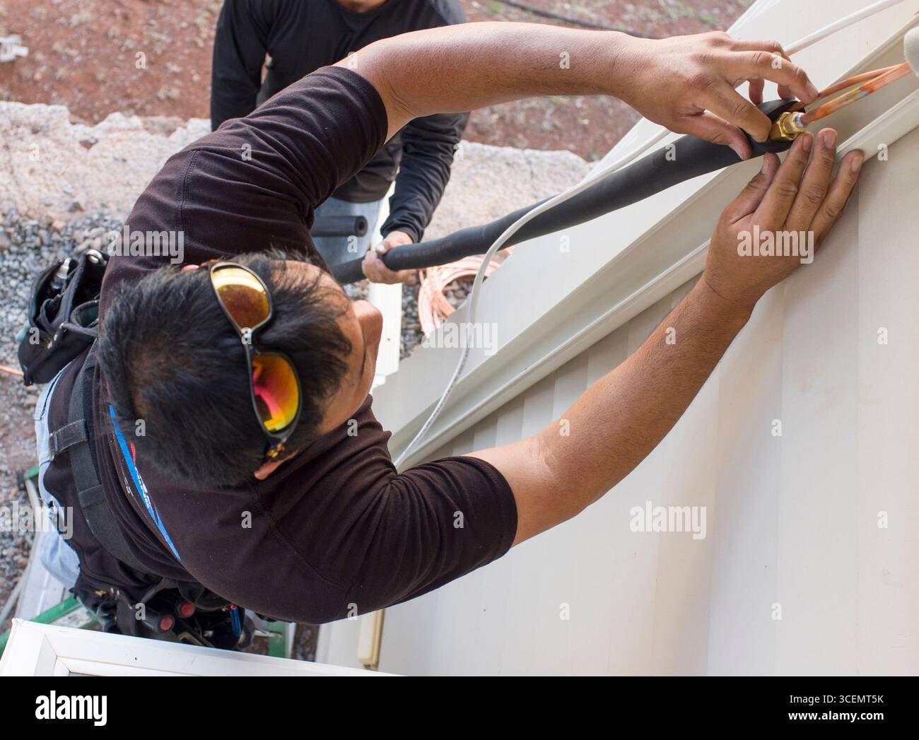 Man covering copper pipe with insulation during installation of Air ...