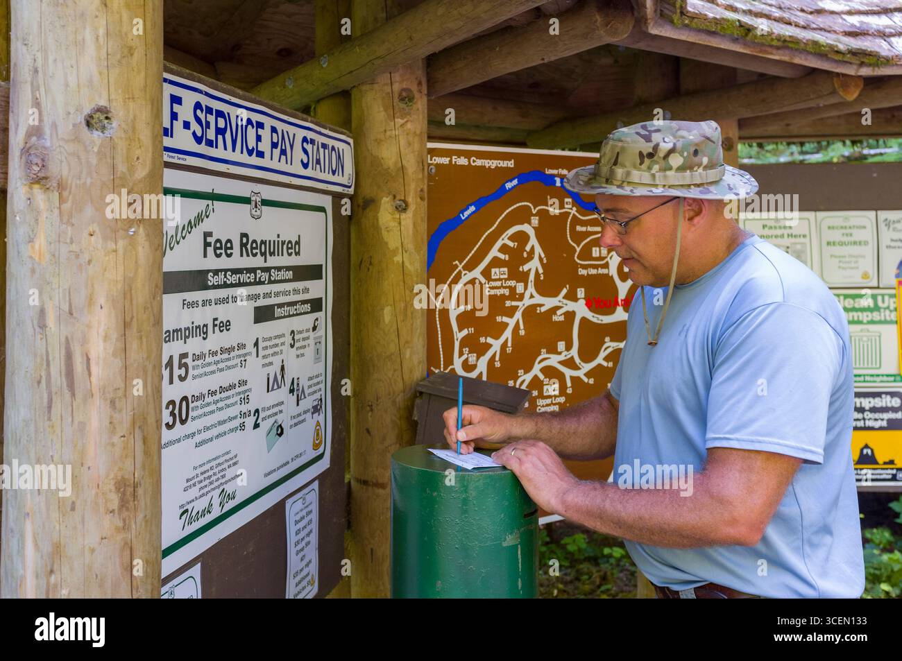 Mature Caucasian man writing on fee envelope at a self-service pay ...
