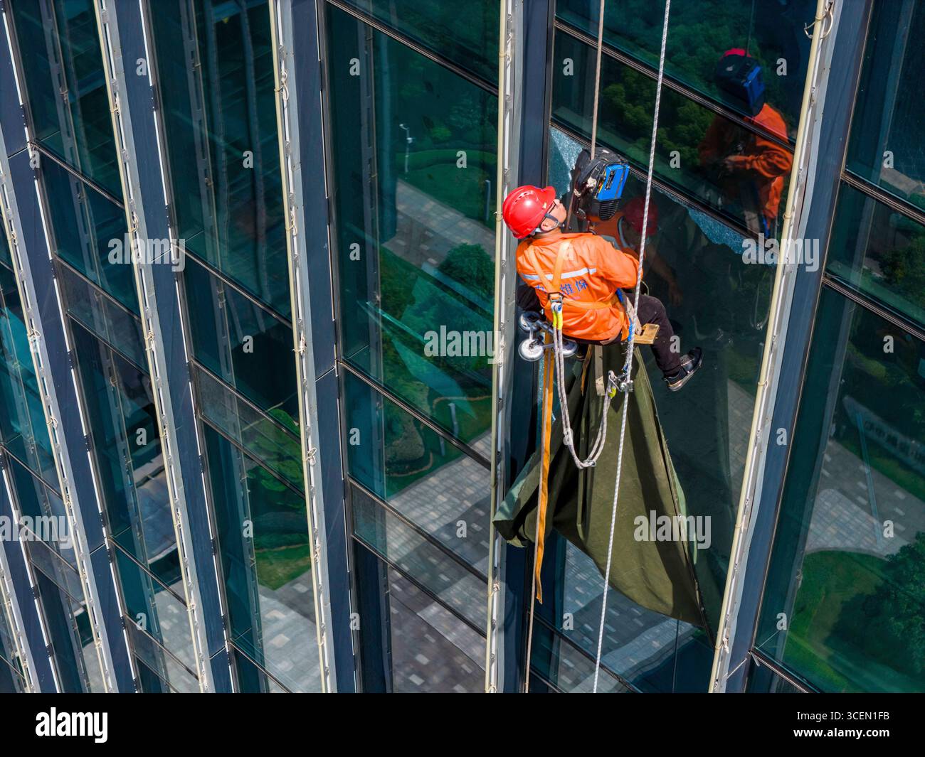 A "spider-man" high-altitude worker replaces a broken glass panel on a ...