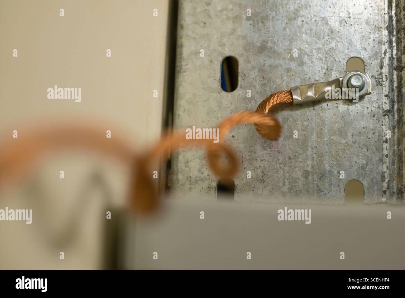 A twisted copper multi-strand grounding wire screwed with a nut to a ...