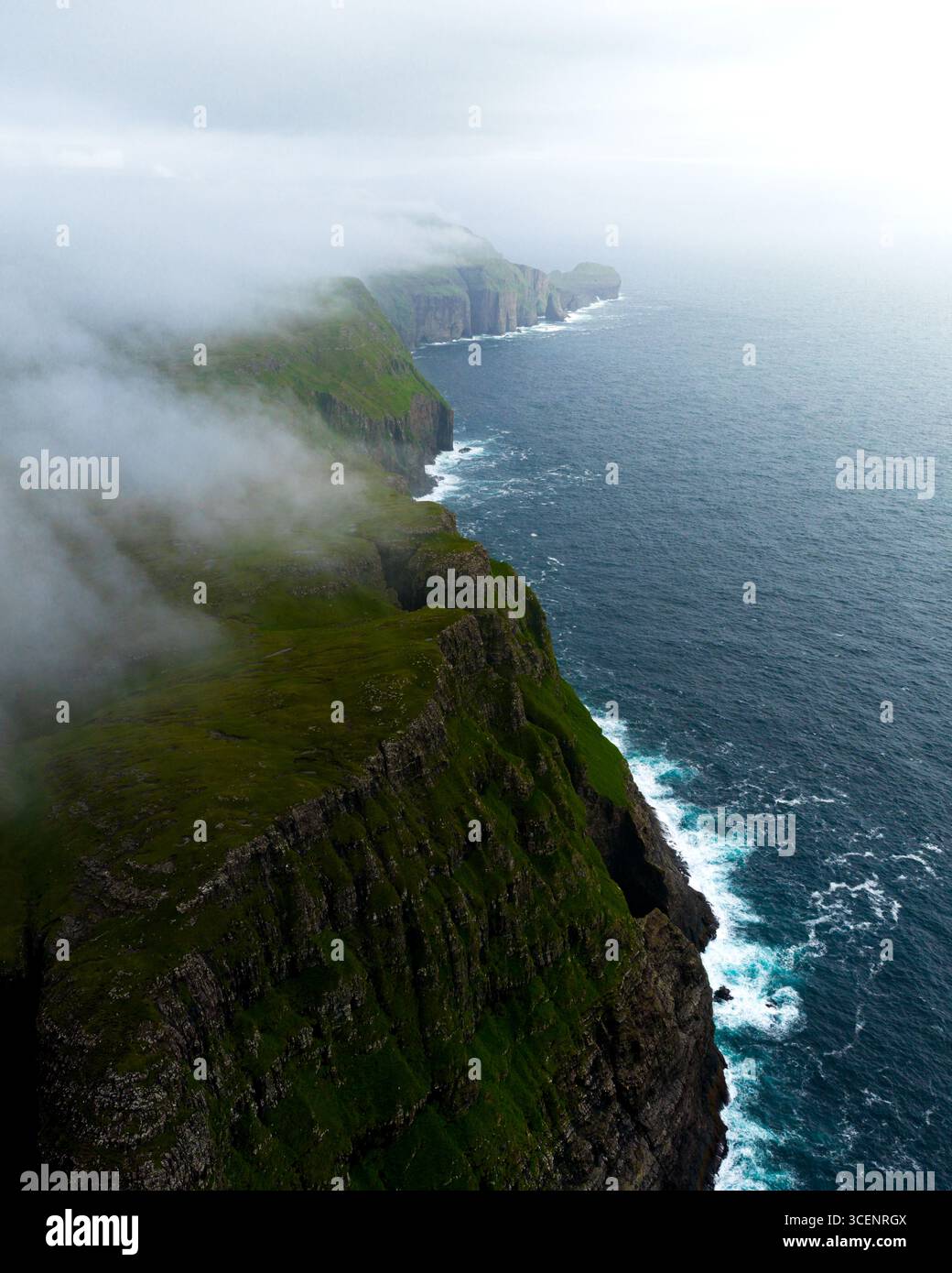 Aerial view of dramatic cliffs plunge into the turbulent sea, shrouded ...