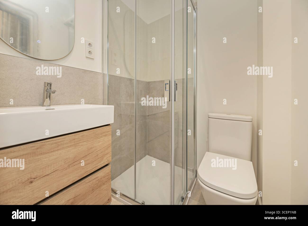 Modern bathroom with a light wood vanity unit and handleless drawers ...