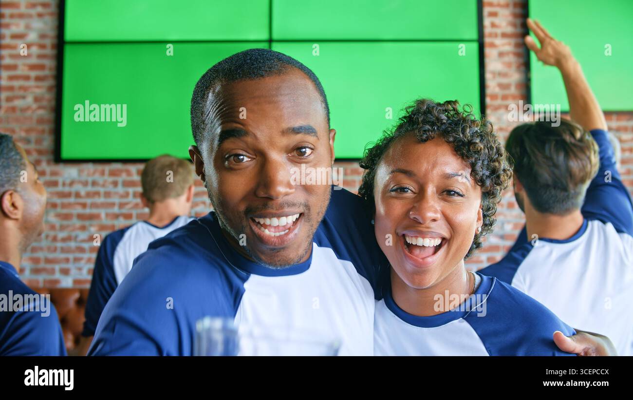 Portrait Of Couple Wearing Team Colours Watching Game In Sports Bar On ...