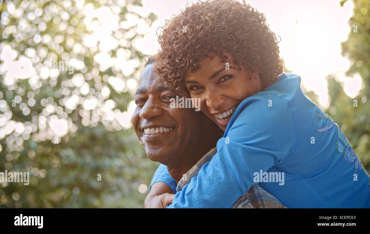 Outdoor Portrait Of Mature Couple With Woman Hugging Man From Behind ...