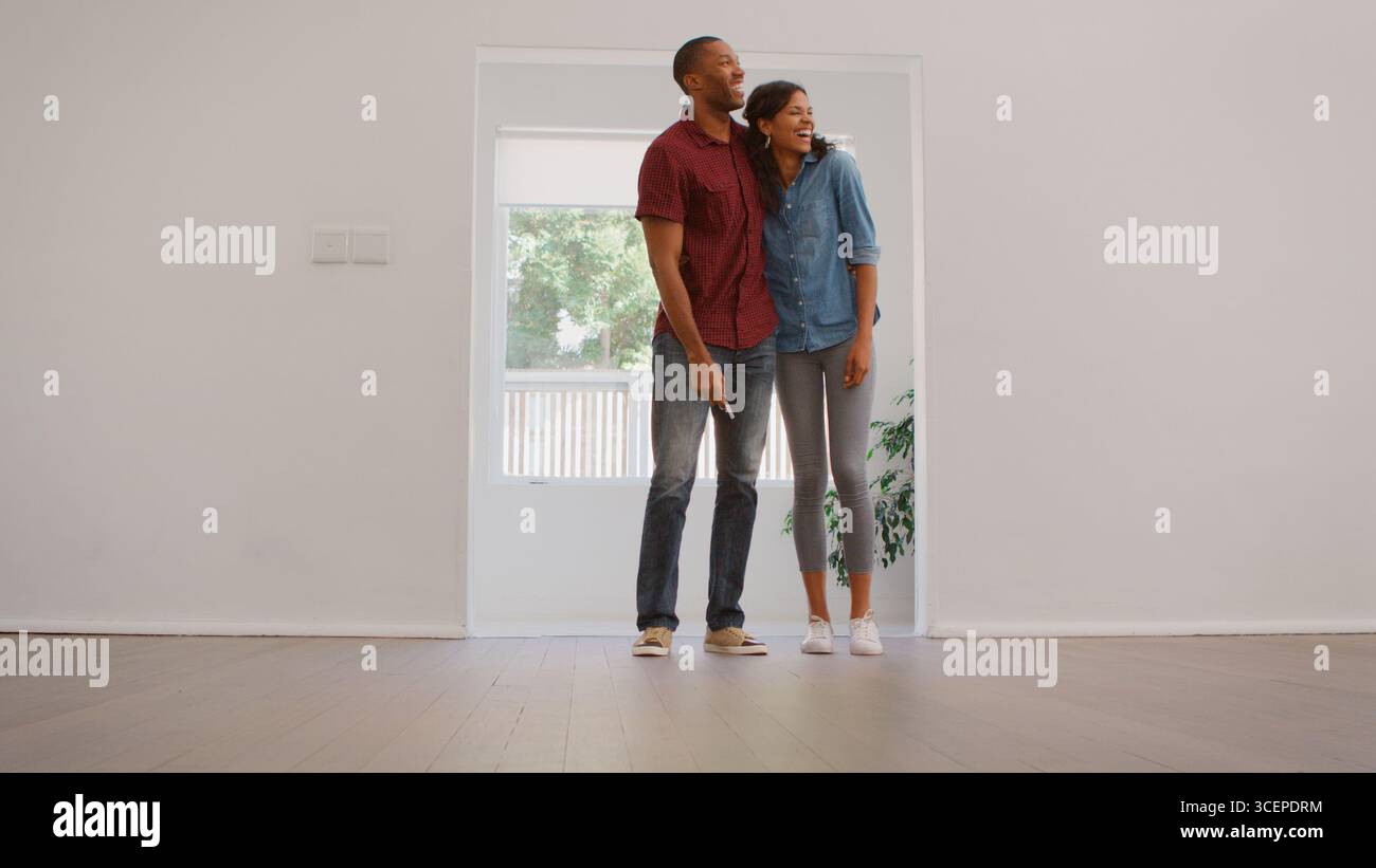 Excited Young Couple Looking Around New Home On Moving Day Together ...