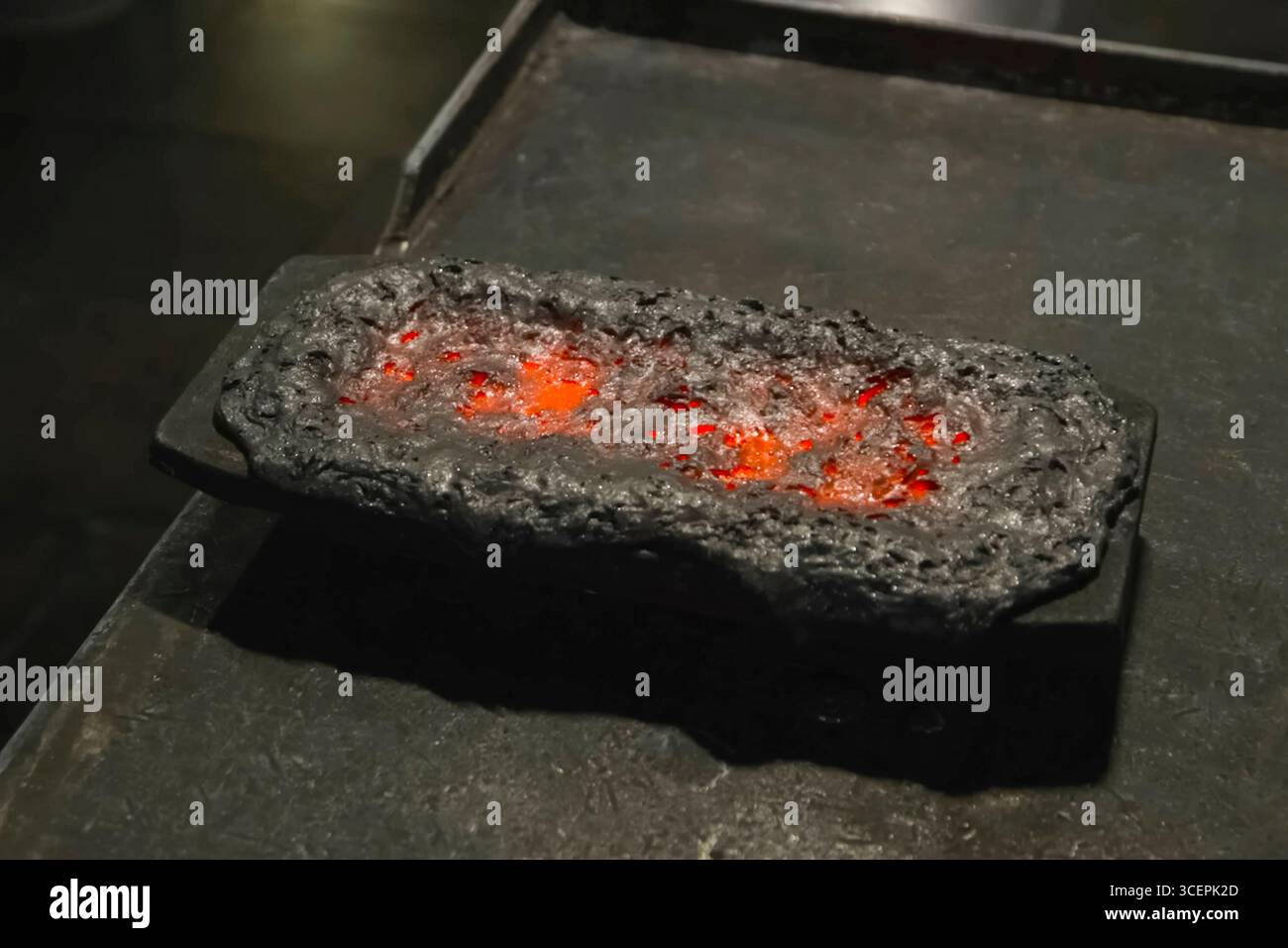 still red with heat, a bar of gold covered with slag in a mold for ...