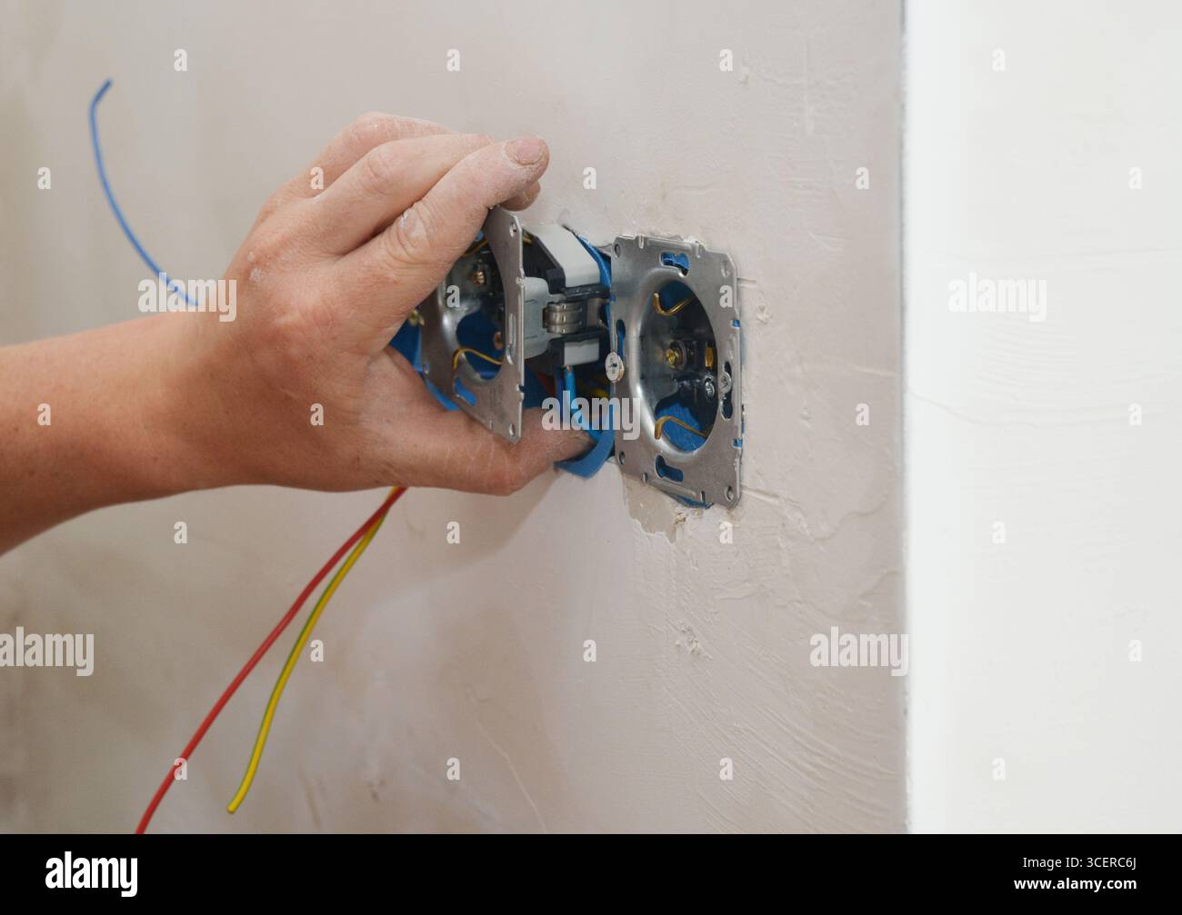 Handyman inserted an electrical outlet into a box in the wall ...