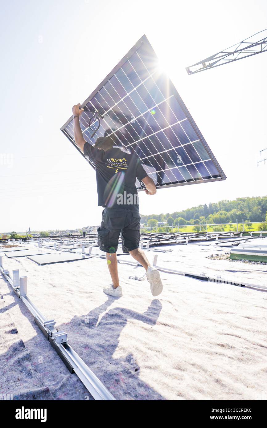 Person carrying solar panel under bright sun on a roof, PV installation ...