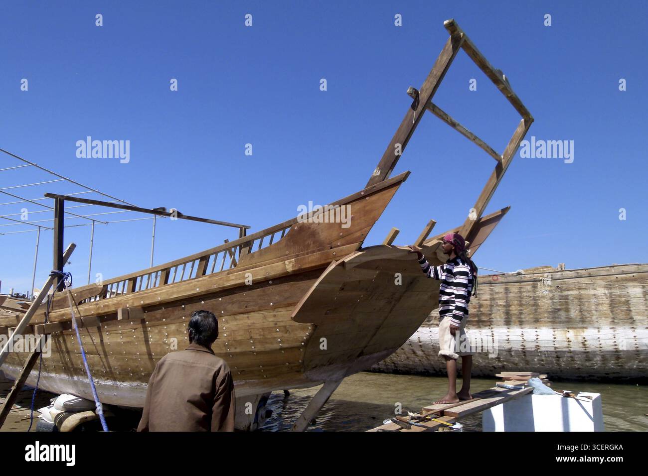 New dhow under construction, shipyard in Sur, two boat builders inspect ...
