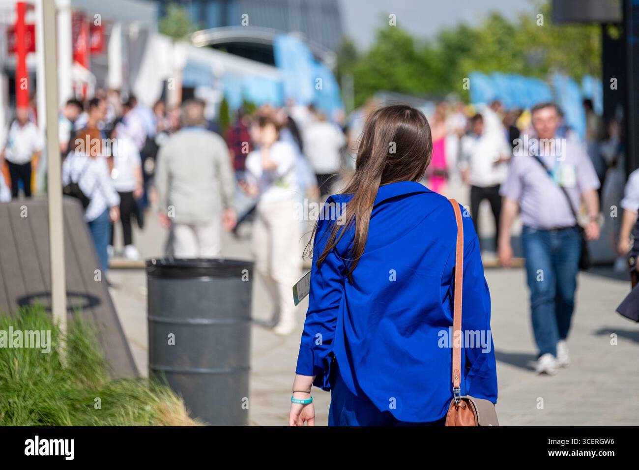 Woman in blue suit walking among crowd at lively outdoor event in ...