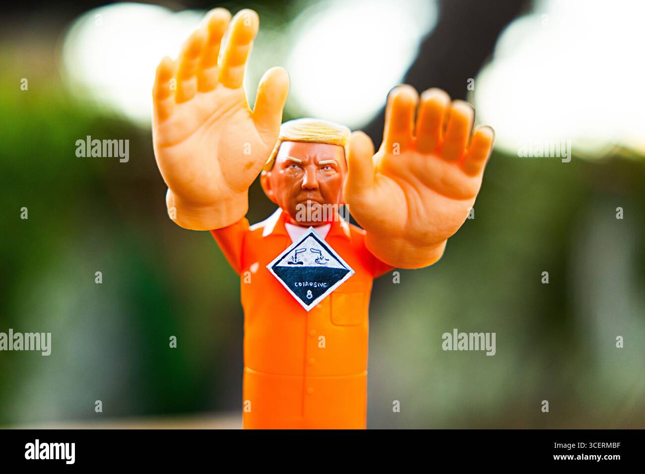 A plastic toy figurine Donald Trump in an orange outfit raises his ...