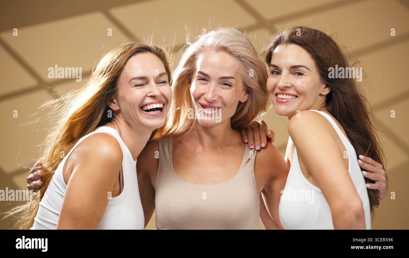 Three women with glowing skin and beautiful hair are joyfully embracing ...