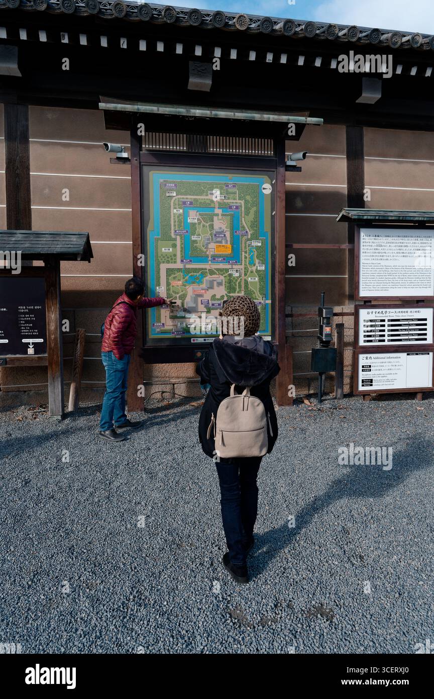 Travelers about to explore the grounds of Nijo Castle, studying a big map at the entrance Stock ...