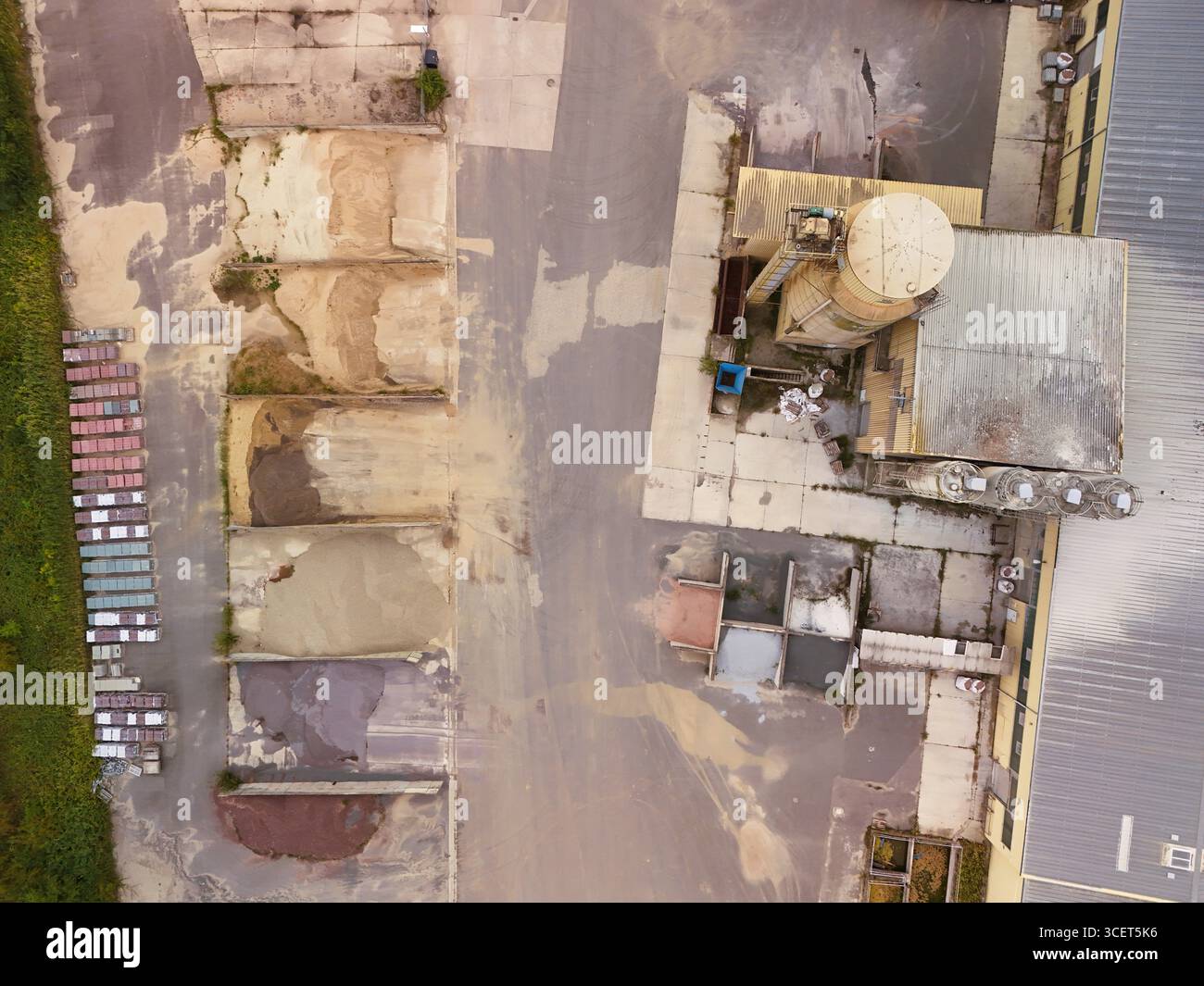 Aerial view of construction material storage yard with silo, sand, and ...