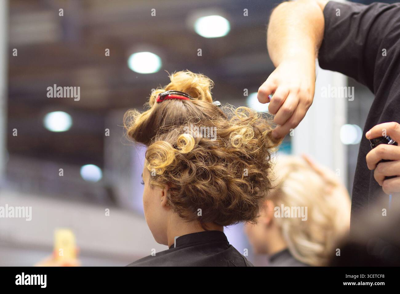 Hairdresser hands using hairspray styling on woman's healthy golden ...