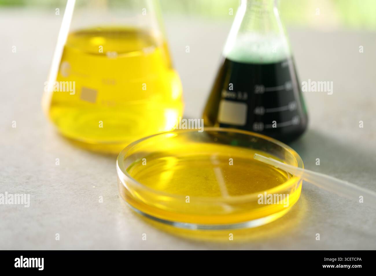 Laboratory glassware with different samples and stirring rod on light ...
