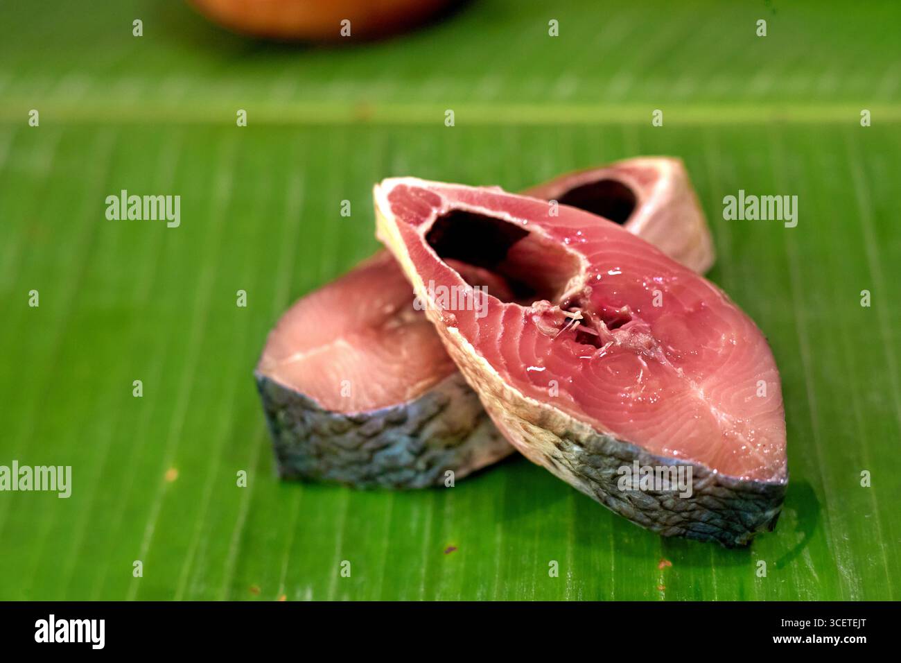 A close-up showcases two thick, circular slices of raw Hilsa fish ...