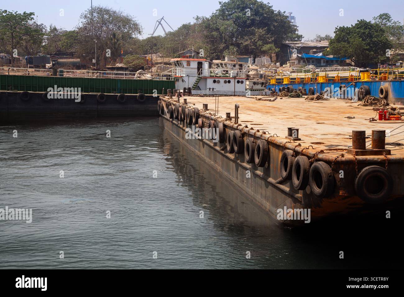 A barge docked at an industrial waterfront, with rubber tires used as ...