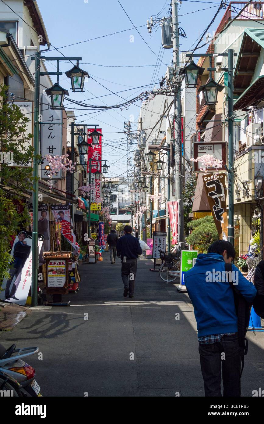 Narrow alley with many signs and wires hanging from utility poles ...