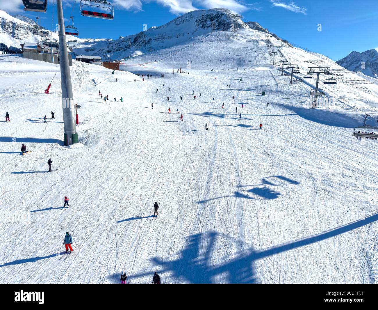 Aerial view of multiple skiers descending sunlit wide slope Stock Photo ...
