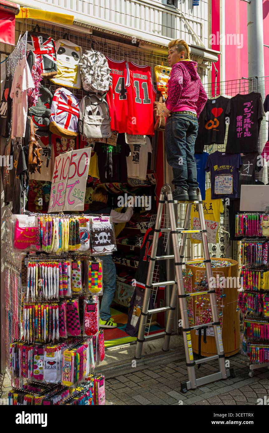 Man with Mohawk haircut standing on top of a ladder hanging clothing ...