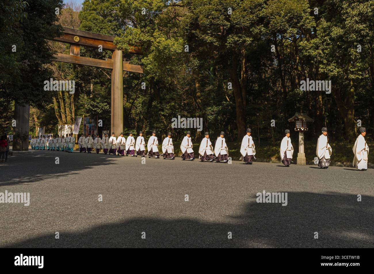 Line of Shinto priests walking through the Torii shrine archway on the ...