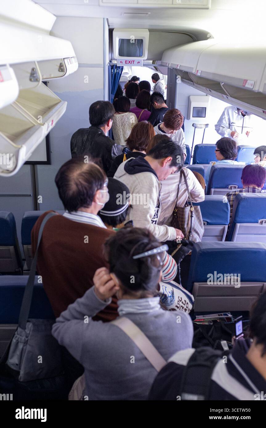 Japanese passenger standing in aisle of a Delta Airlines 747 aircraft ...