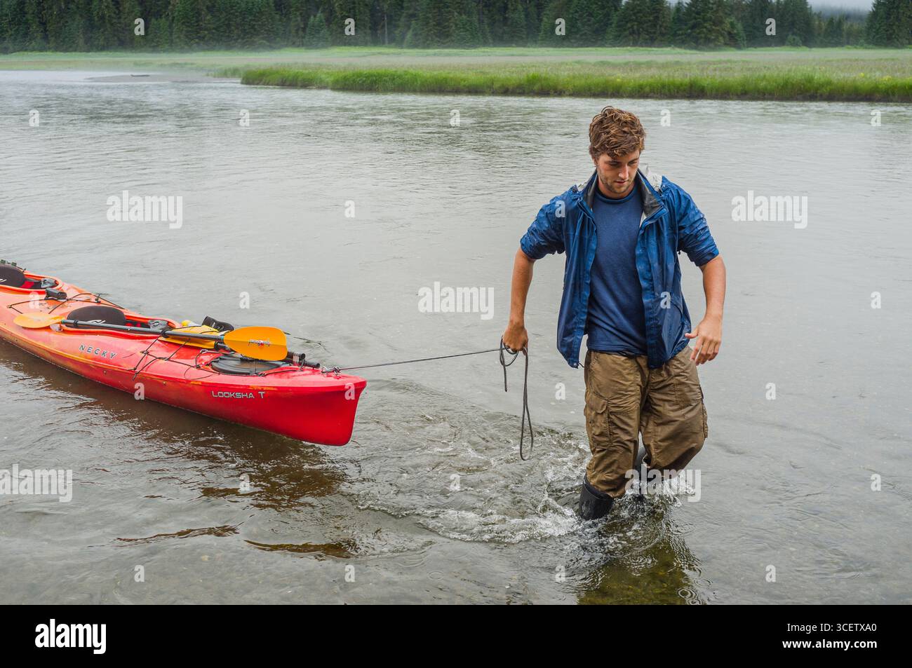 Young Caucasian man pulling orange plastic tandem kayak up the Salmon ...