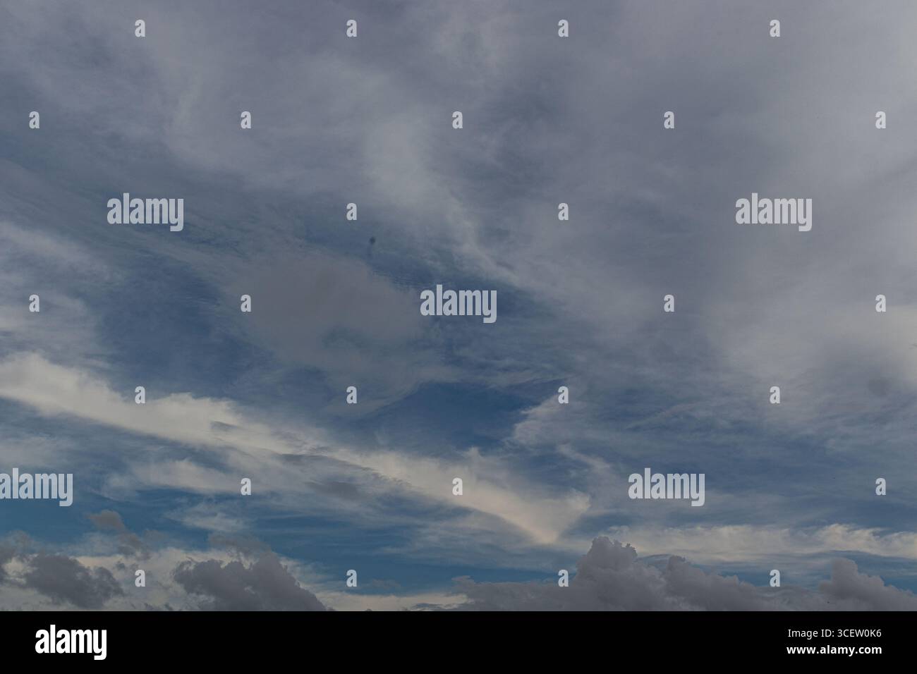 Dramatic cloudy blue sky with soft white streaks and scattered cumulus ...
