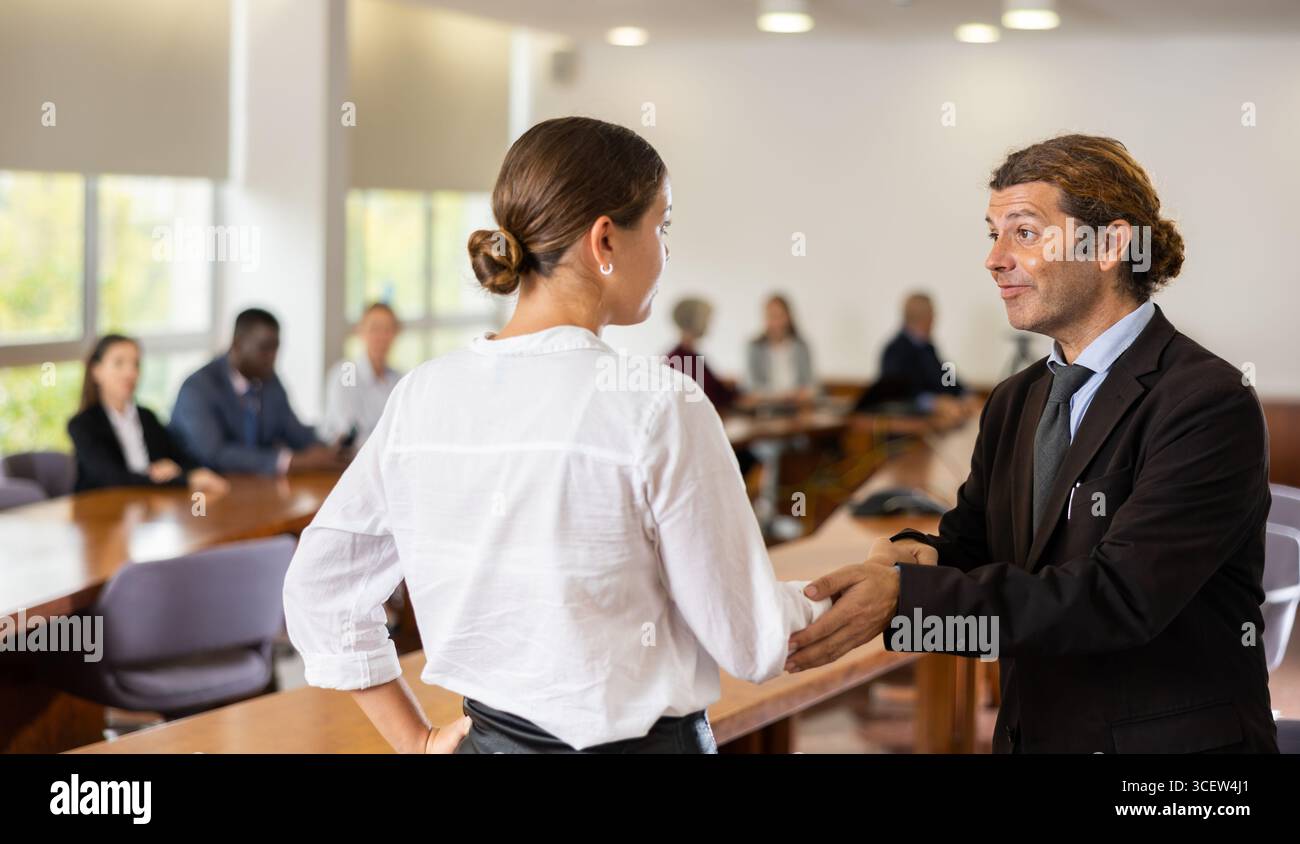 Middle aged white male manager welcoming a new white female employee ...