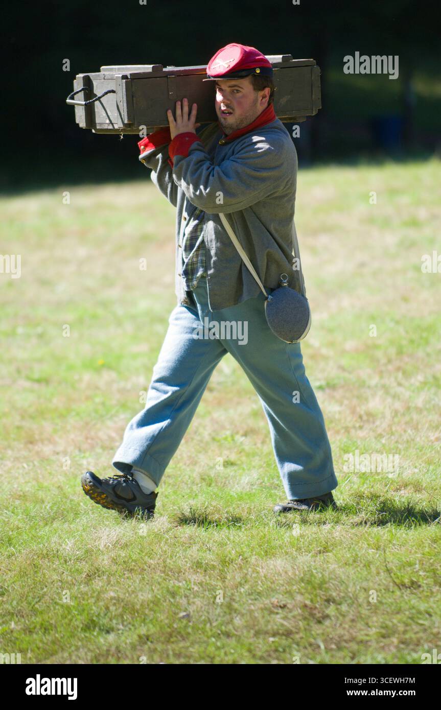 Man dressed in military uniform carrying a wooden crate on his shoulder ...