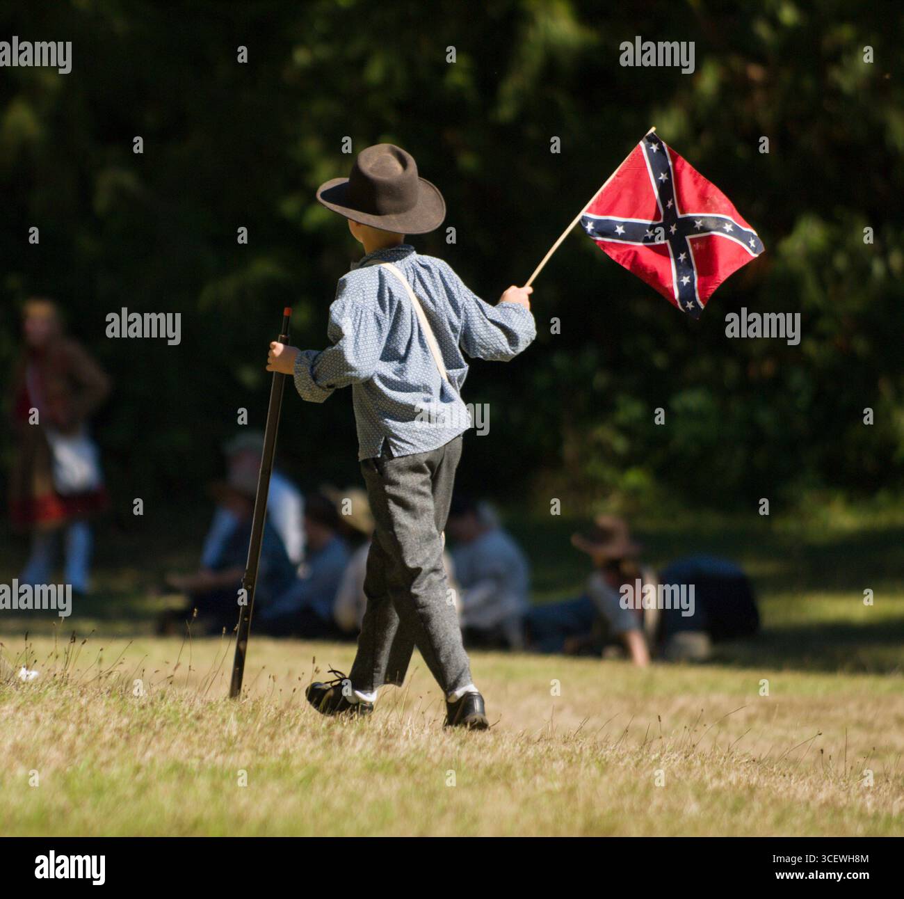 Boy dressed in period costume waving small confederate flag at Civil ...