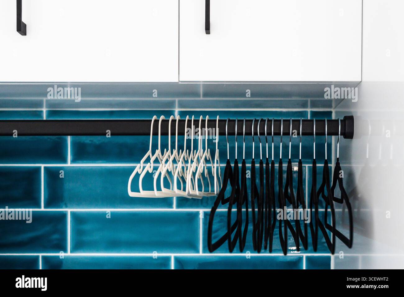 tidy matching hangers in laundry room with white cabinets black handles ...