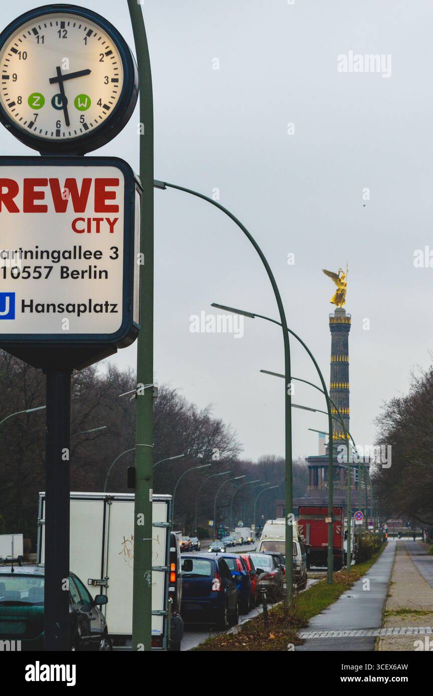 Berlin street with traffic, a REWE sign and clock in front, and the ...