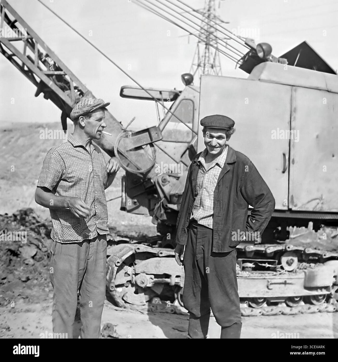 Two workers on a smoke break near a crawler crane at the construction ...