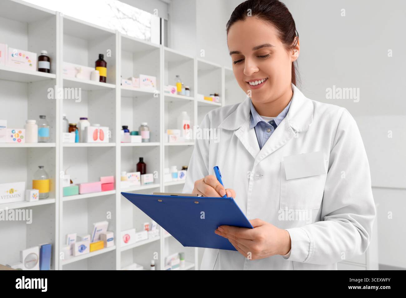 Female pharmacist writing in clipboard at pharmacy Stock Photo - Alamy