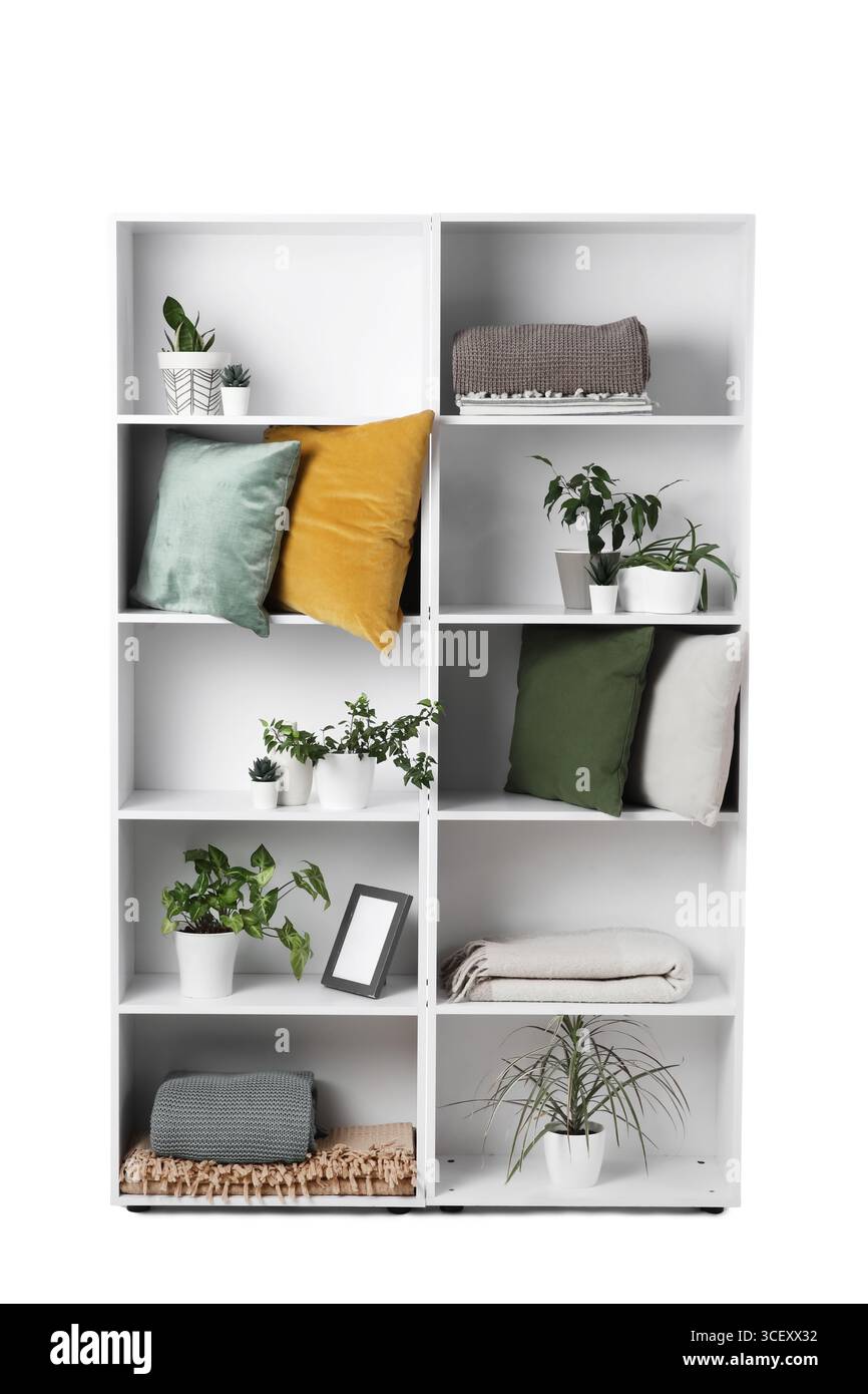 Shelf unit with green plants and pillows on white background Stock ...