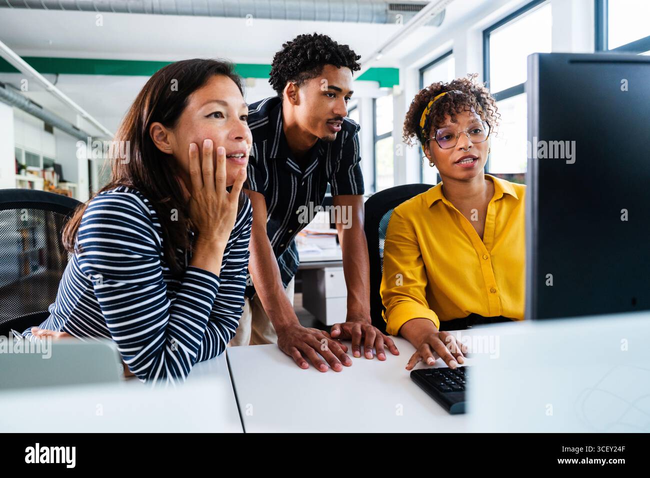 Three diverse colleagues are actively engaged in a collaborative ...