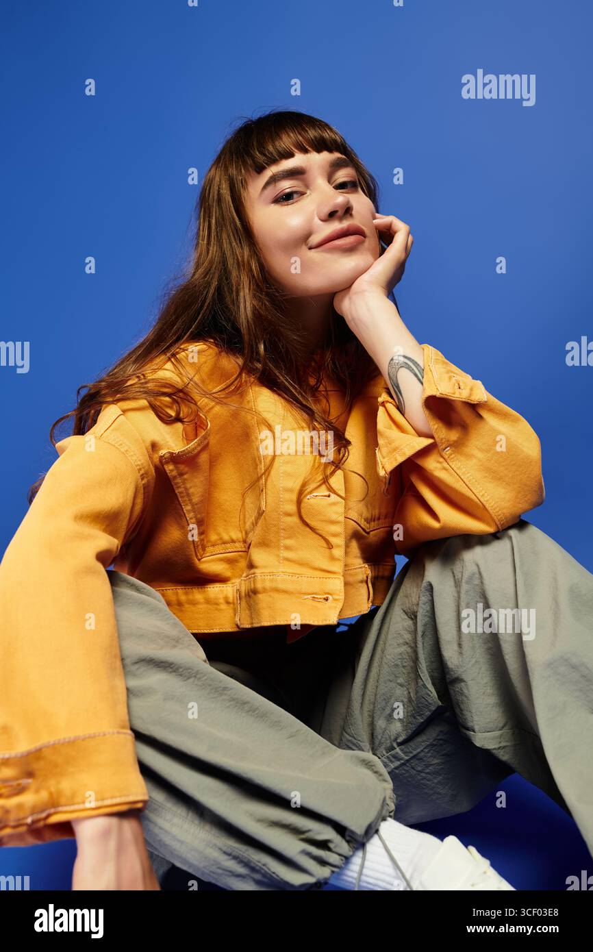 A young woman models her trendy outfit, playfully resting her chin on ...